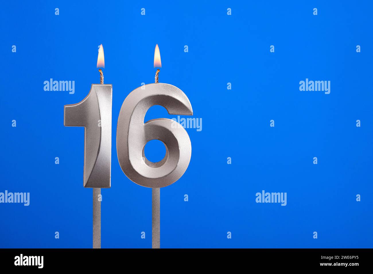 Birthday number 16 - Candle lit on blue background Stock Photo - Alamy