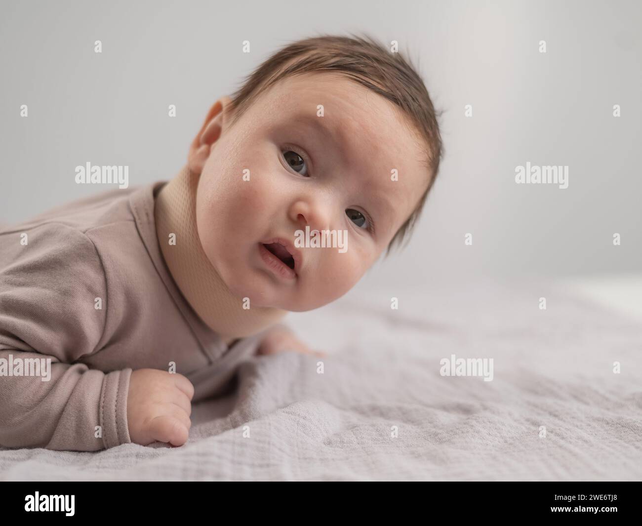 Portrait of a newborn baby lying on his stomach in an orthopedic collar ...