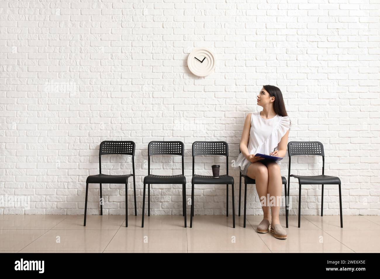 Young woman looking at clock while waiting for job interview in room ...