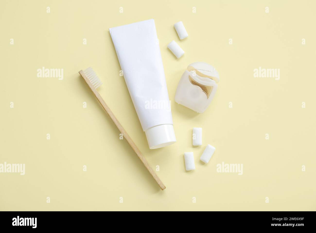 Toothpaste with brush, dental floss and chewing gums on light yellow ...