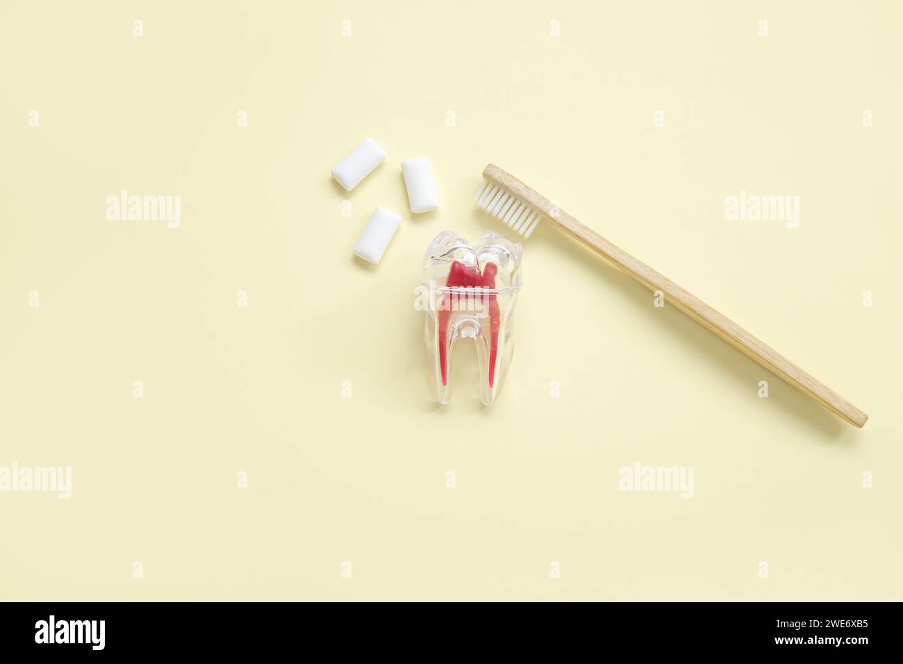 Plastic tooth with brush and chewing gums on light yellow background ...