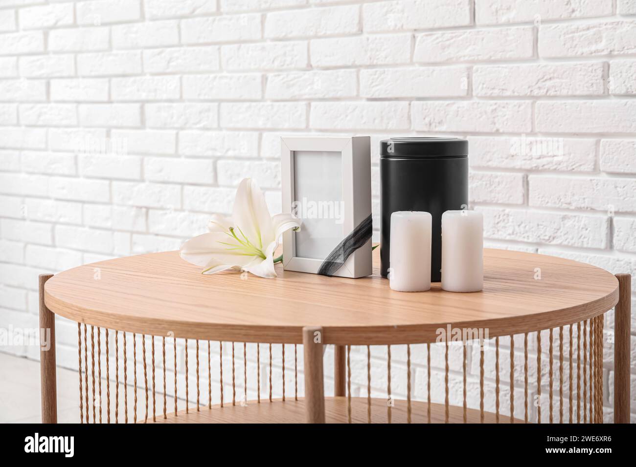 Blank funeral frame, mortuary urn, candles and lily flower on wooden ...