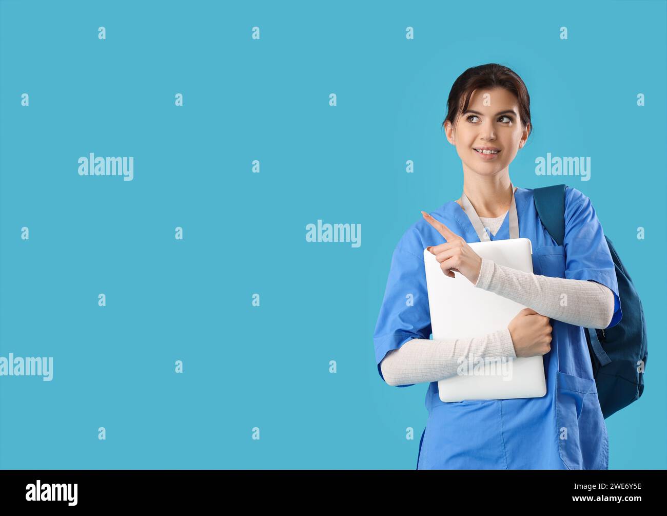 Female medical intern with laptop pointing at something on blue ...