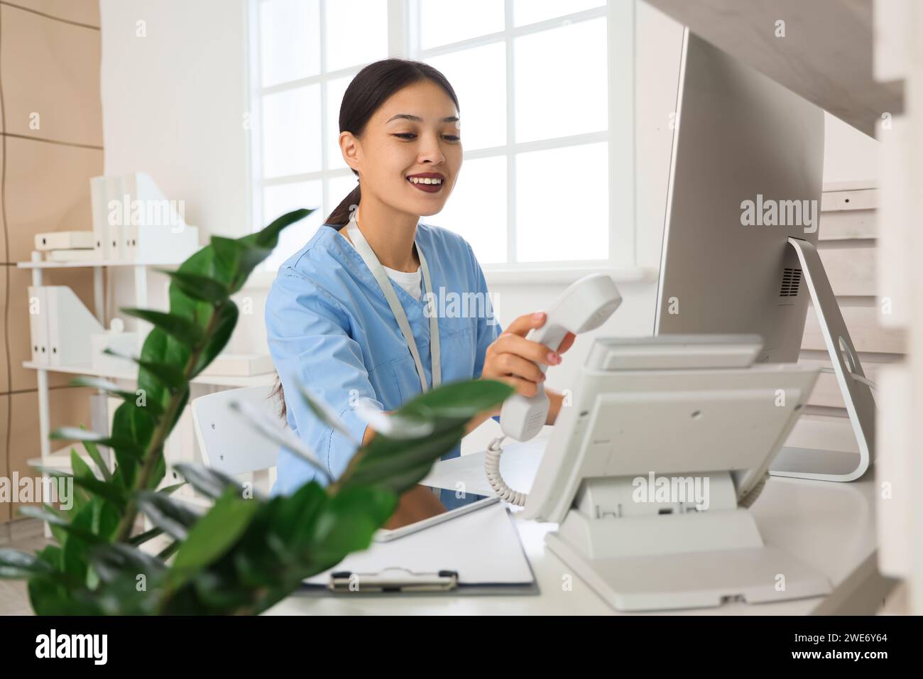 Female Asian medical intern with telephone at reception in clinic Stock ...