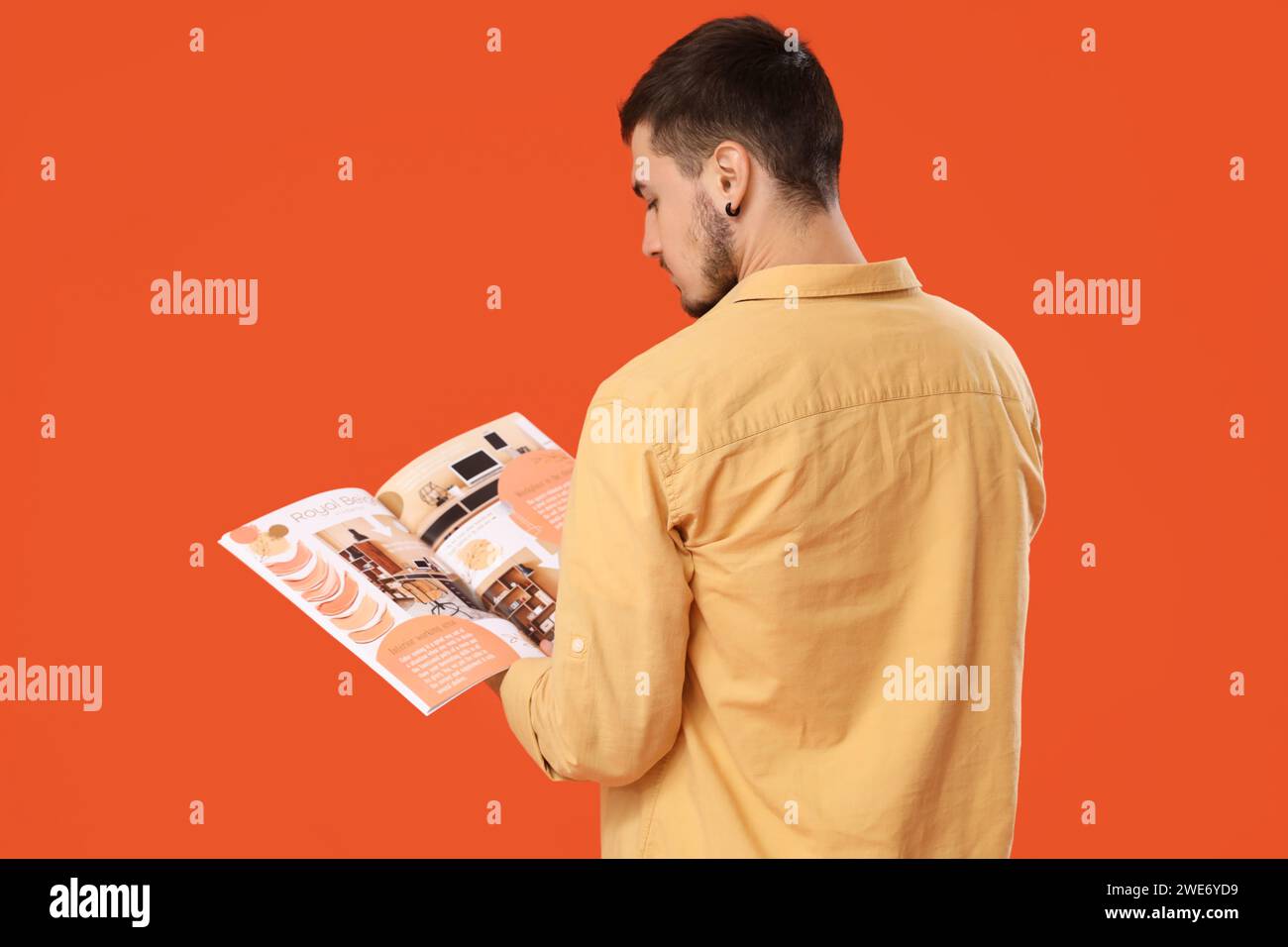Young man reading magazine on orange background, back view Stock Photo ...