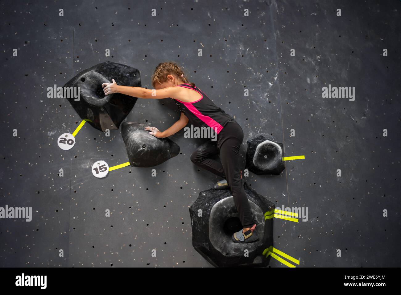 Side view of determined girl climbing artificial wall. Brave and strong ...