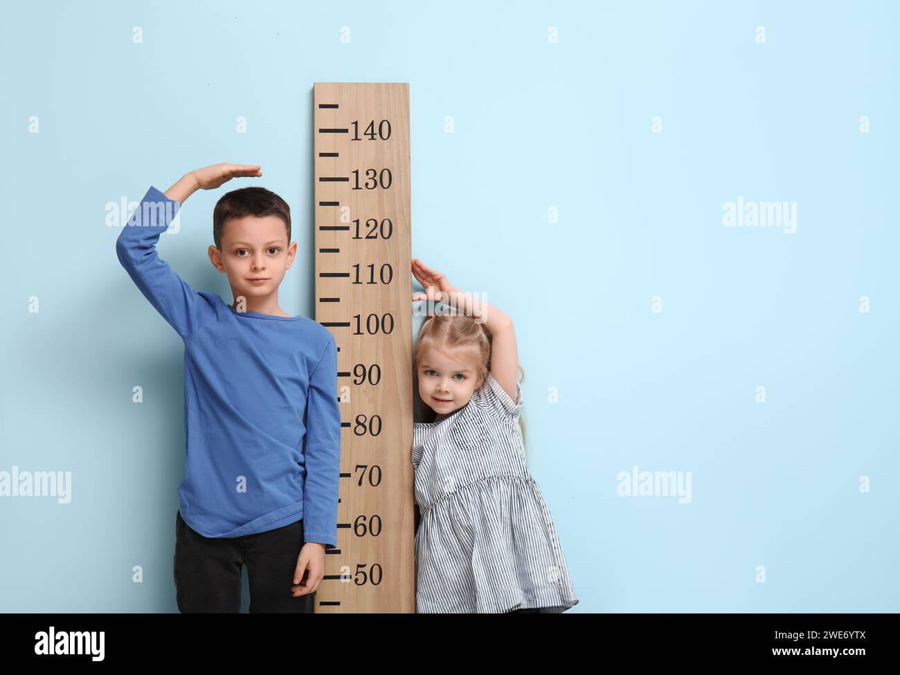 Cute little children measuring height on blue background Stock Photo ...
