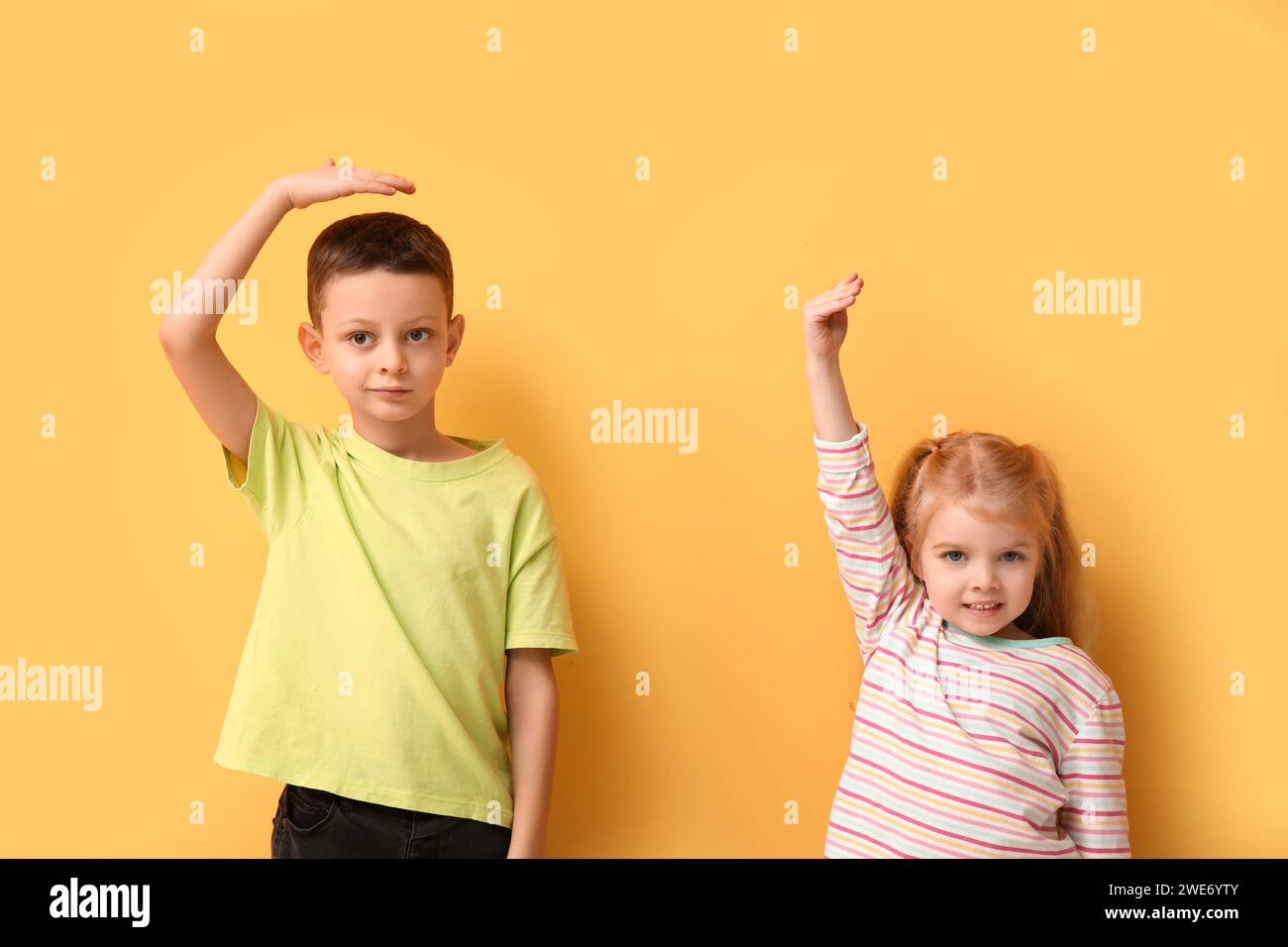 Cute little children measuring height on yellow background Stock Photo ...
