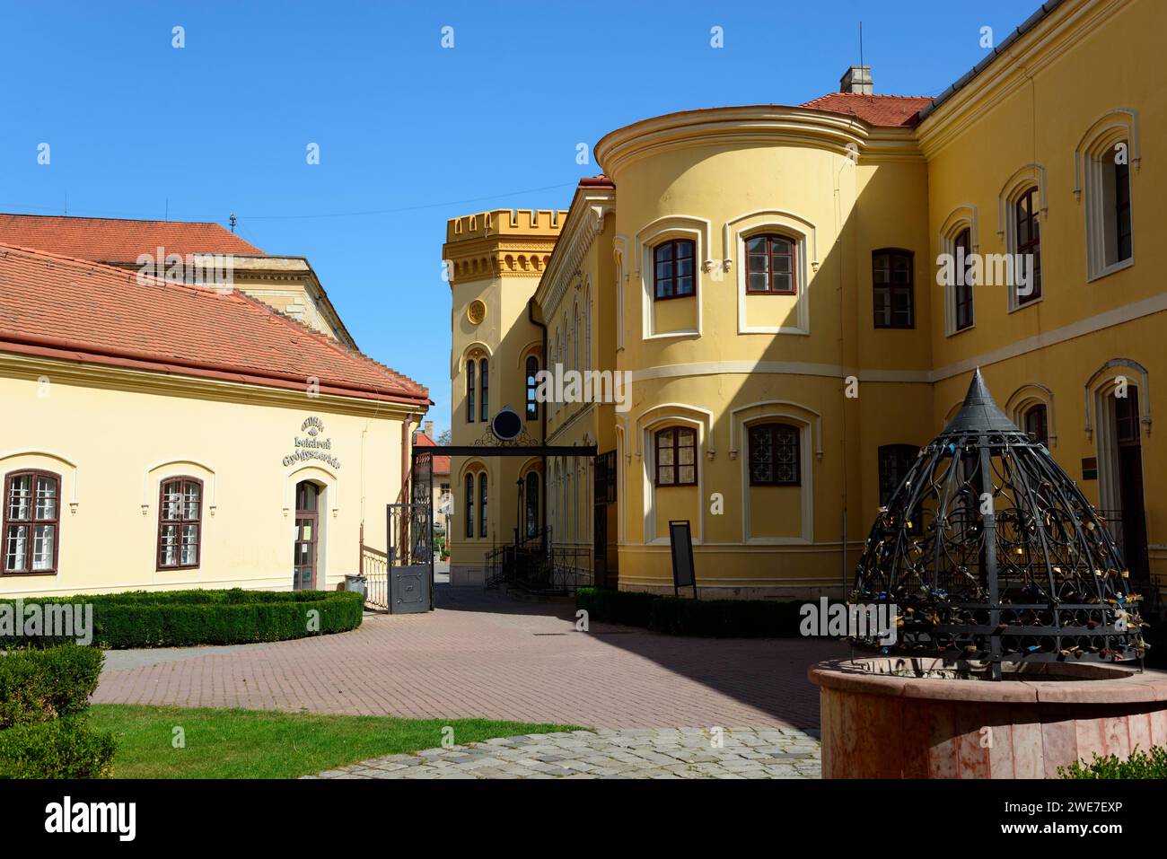 A castle courtyard with yellow facades, a sculpture and a fountain on a ...