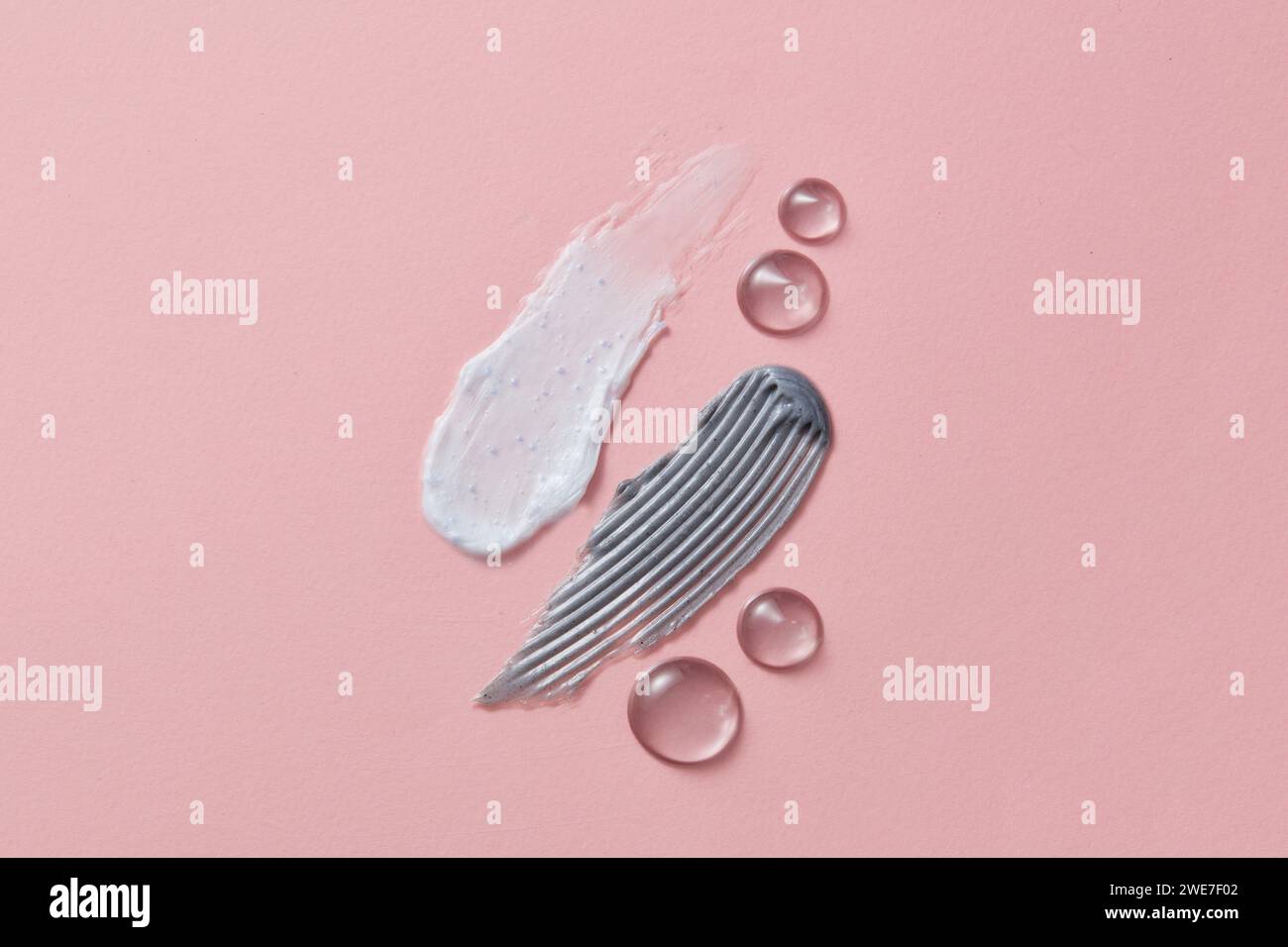 Over the pink background, two cosmetic smears in white and gray color ...