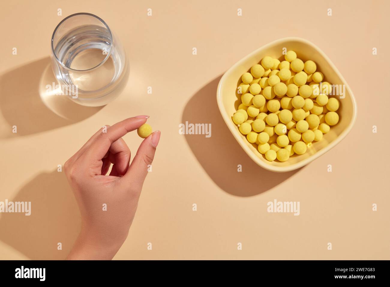 Many turmeric starch tablets are filled in a pastel bowl against beige ...