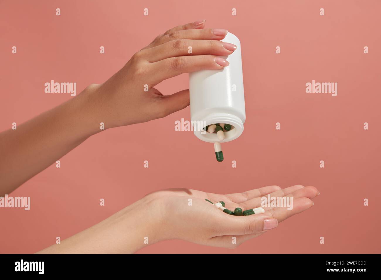 Many capsules are poured from a medicine bottle in white color into a ...