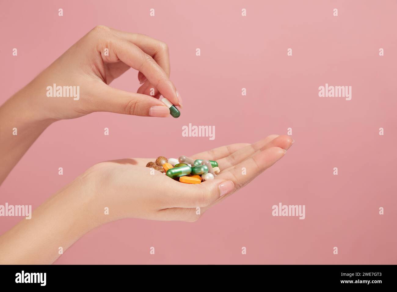 A stack of many tablets, capsules and pills on a female hand against ...