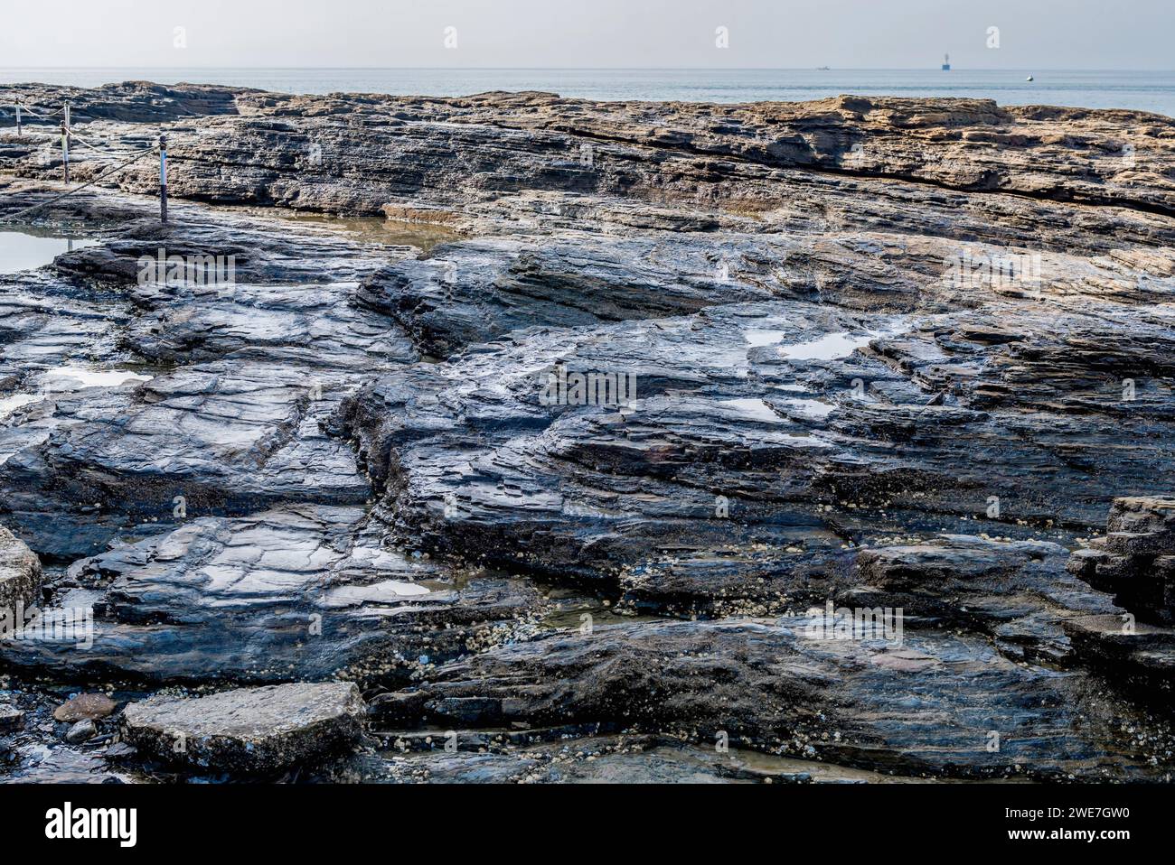 Stratified geological rocks with layers of various shapes with ocean in ...