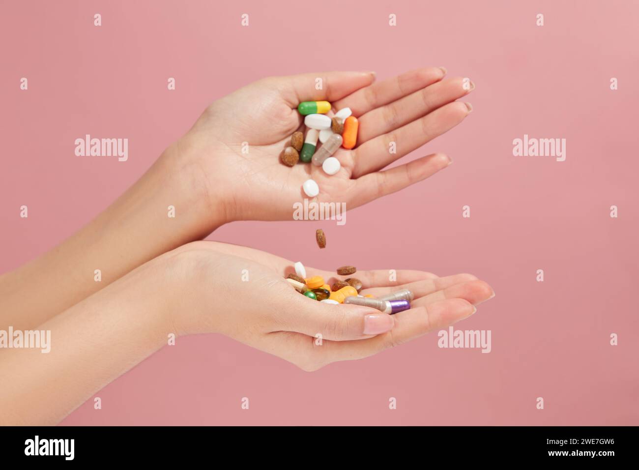 Multicolor pills, tablets and capsules are arranged on both hands with ...
