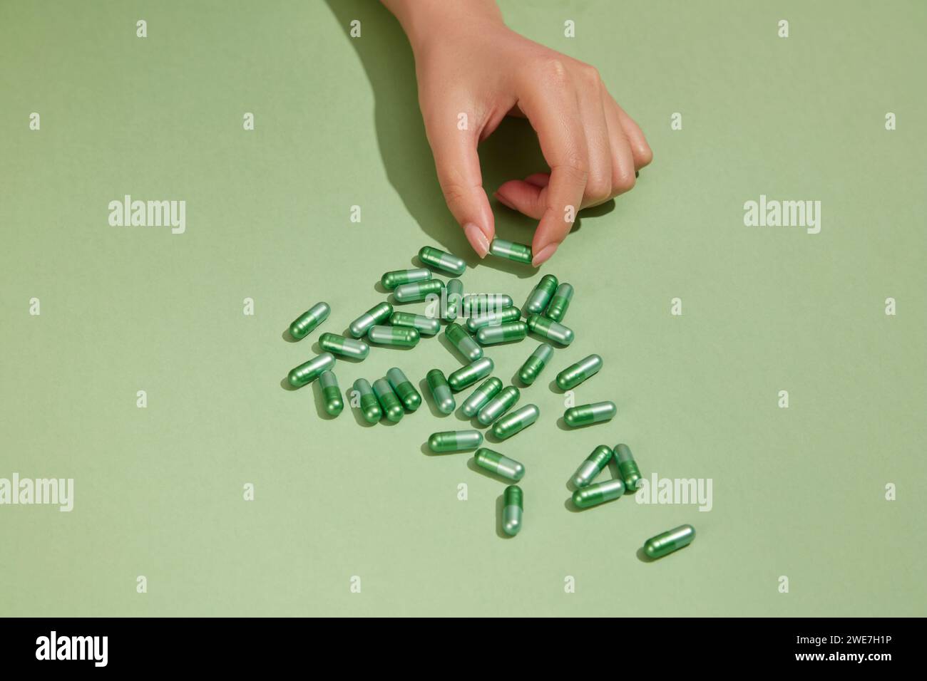 Hand model picking up a green capsule from a lot of capsules. Medicines ...
