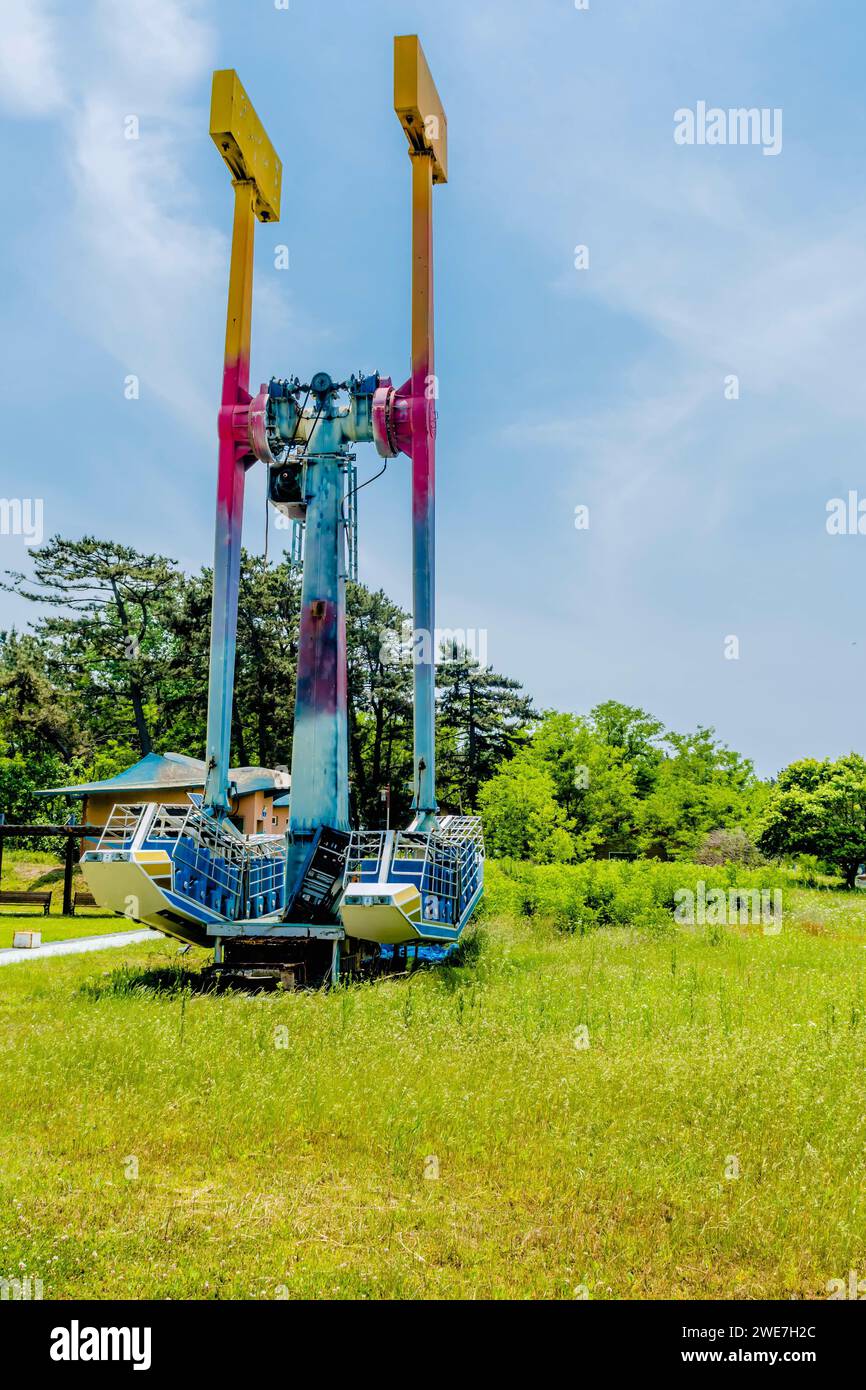 Broken abandoned carnival ride in rural park with cloudy blue sky in ...