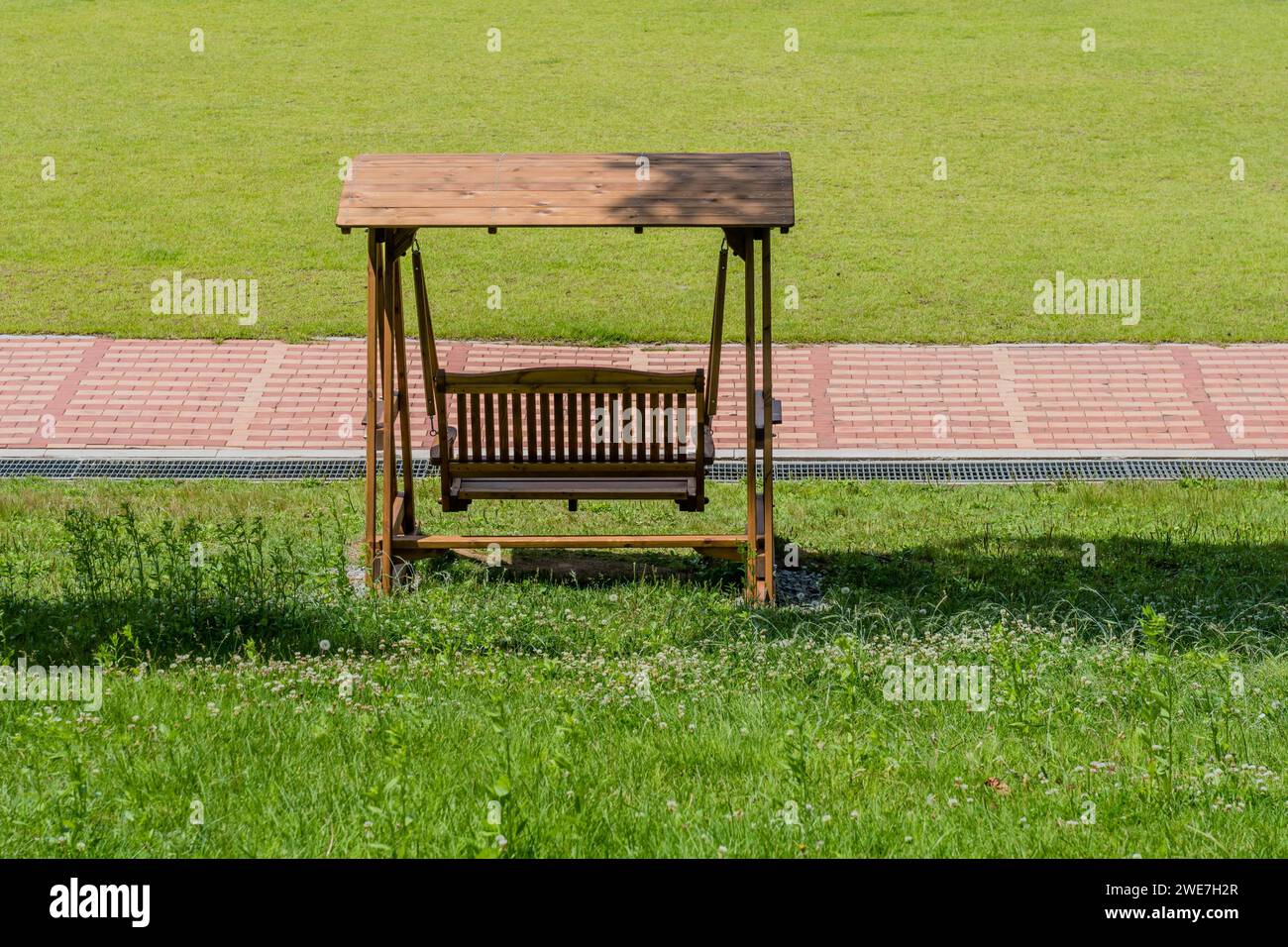 Rear view of wooden swing park bench beside walkway in South Korea Stock Photo - Alamy