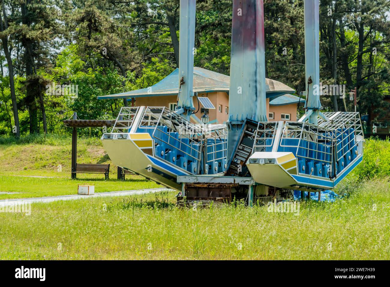 Broken abandoned carnival ride in rural park with trees in background ...