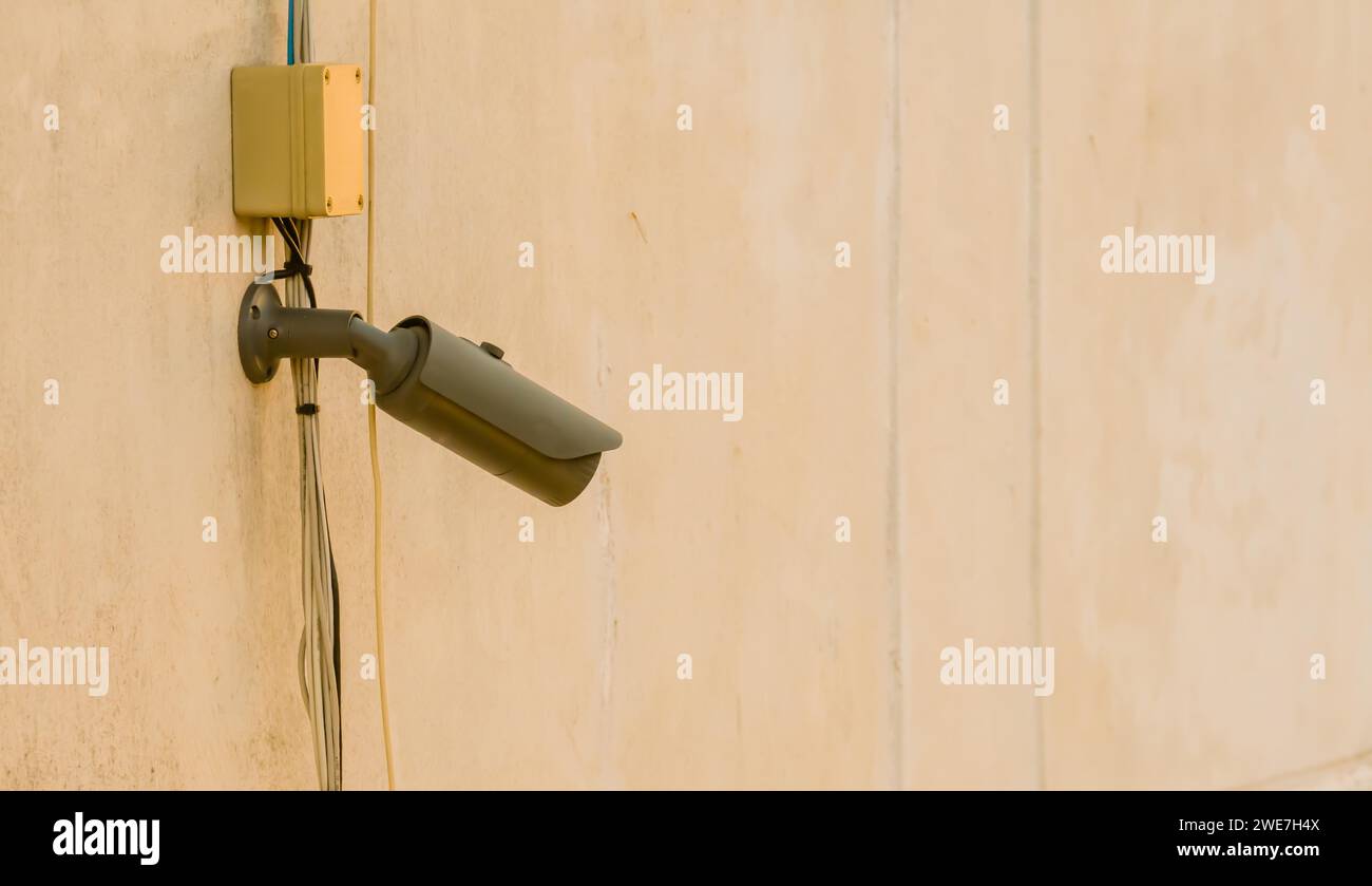 CCTV security camera and associated wires mounted under window on side ...