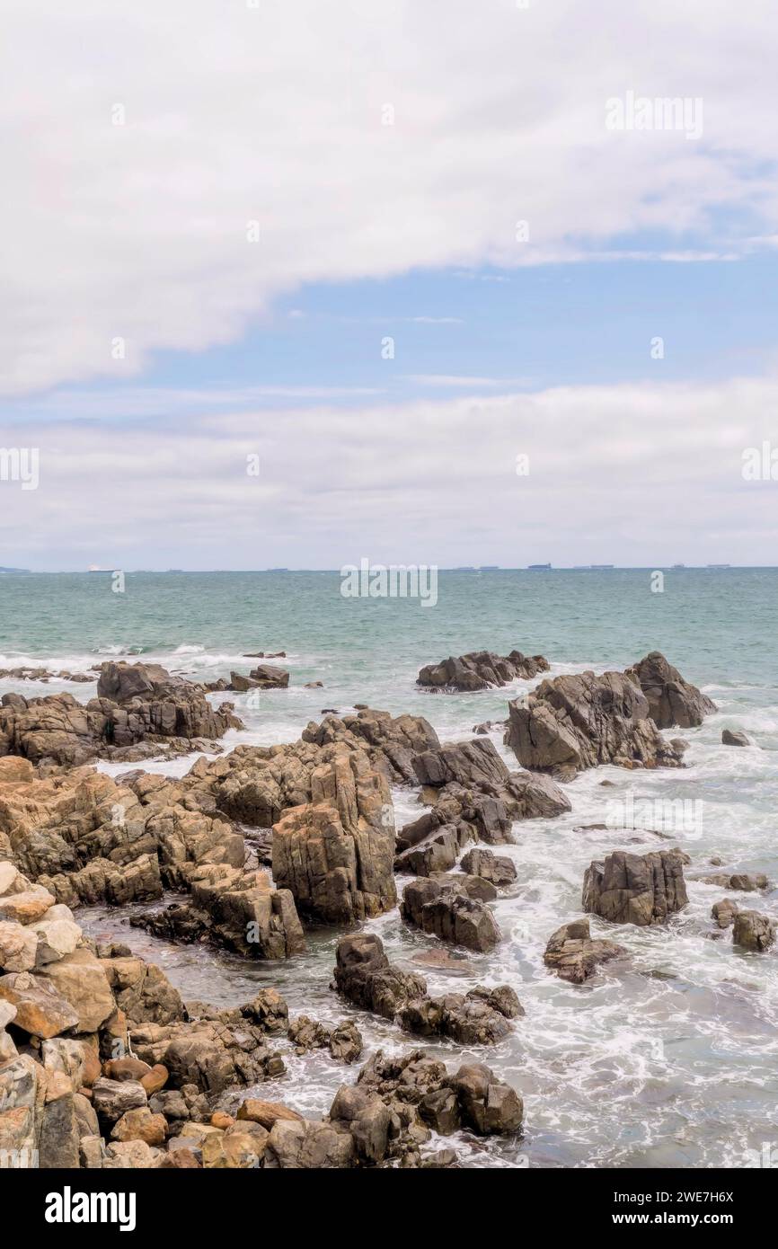 Rock formations in ocean cove near craggy coastline with ships on ...
