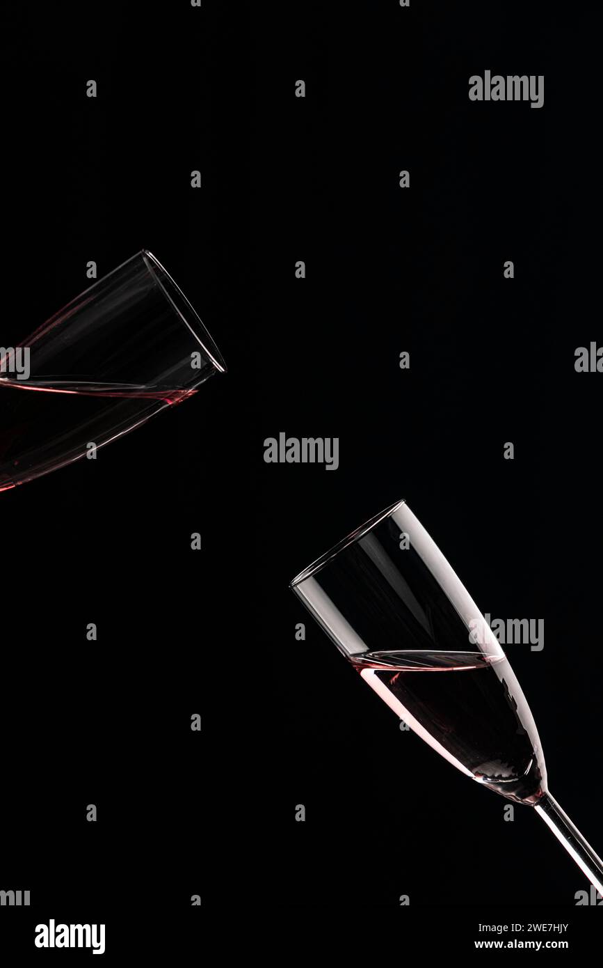 Two half-filled champagne glasses tilted towards each other against a ...