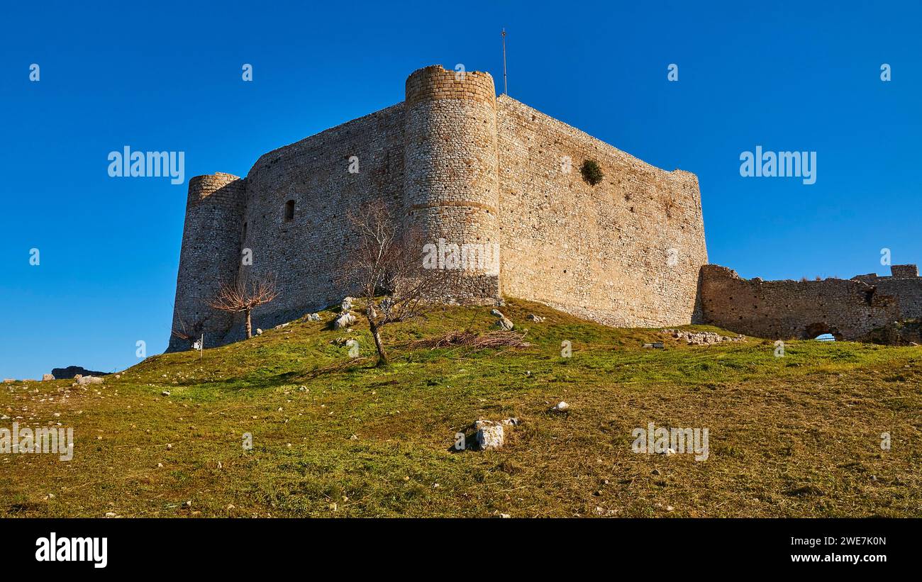 Ancient stone castle on a hill with green grass and clear blue sky ...