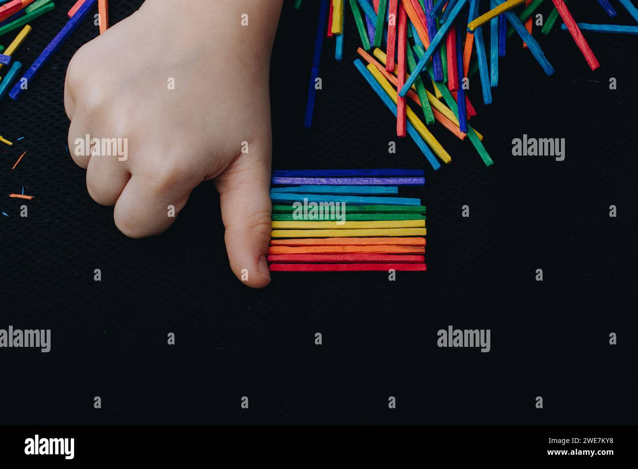 Kid playing with coloured wooden sticks for creativity on white ...