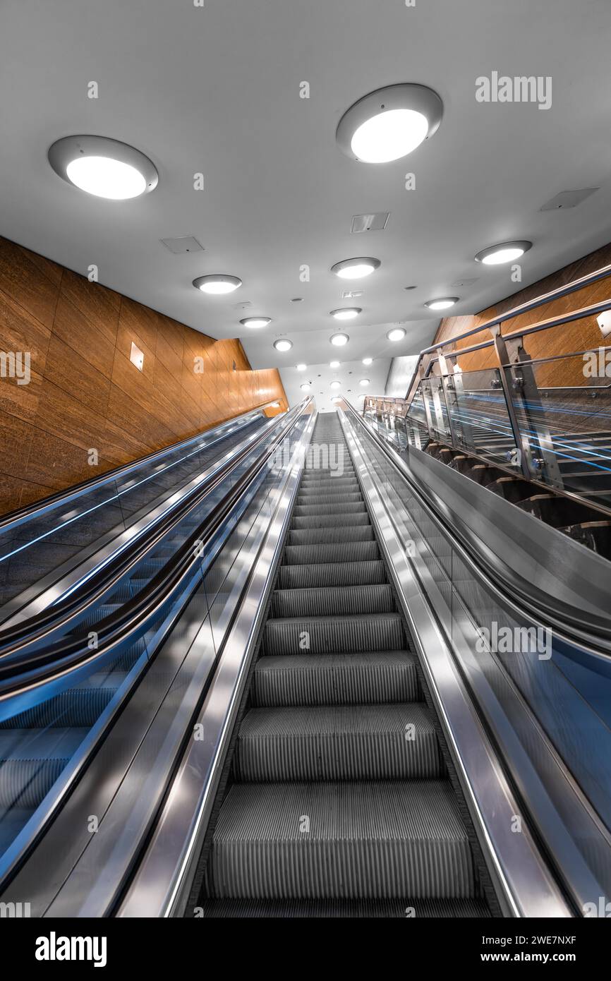 Modern escalator in an interior with striking symmetrical lighting ...
