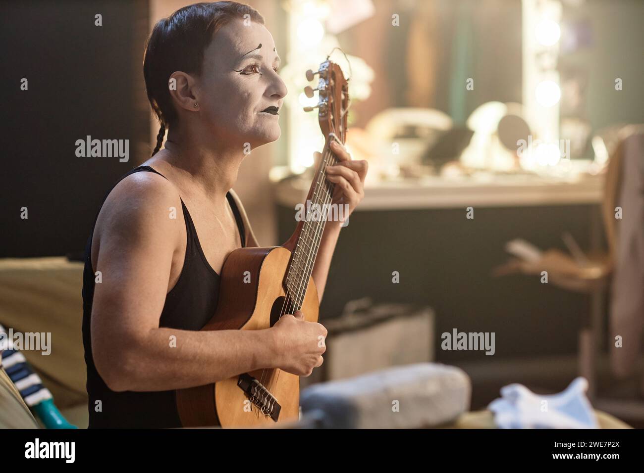 Side view portrait of female mime performer playing ukulele while ...