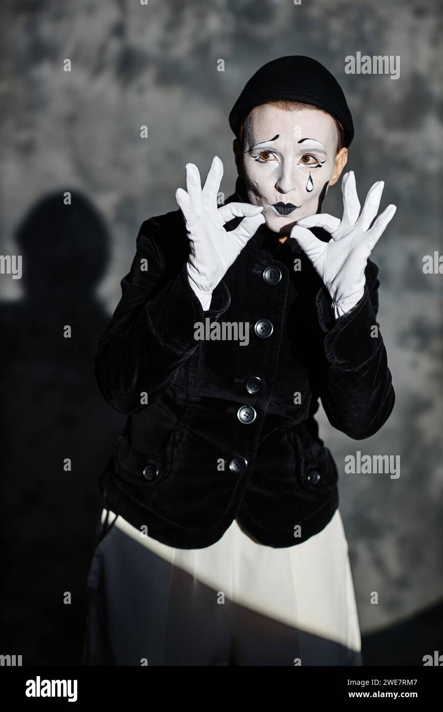 Dramatic vertical portrait of female mime artist standing on stage in ...