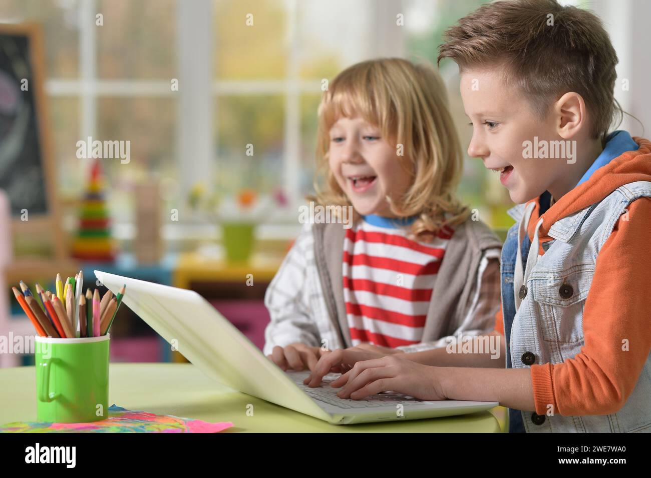 Two boys at class using laptop and writing Stock Photo - Alamy