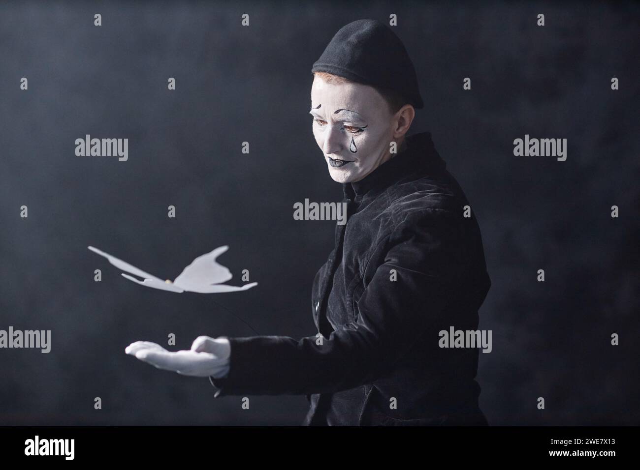 Waist up portrait of mime performer acting on stage in spotlight with ...