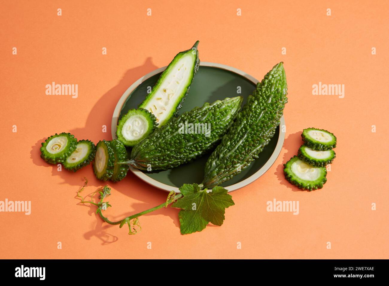 Over a pastel background, a dish of fresh green bitter melon is ...