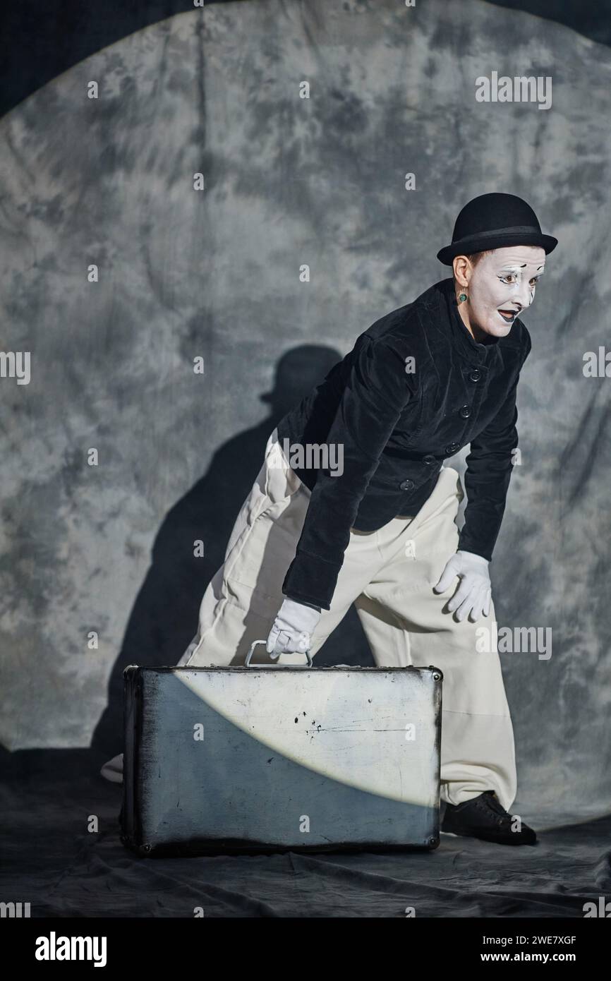Vertical full length portrait of mime artist performing act with ...