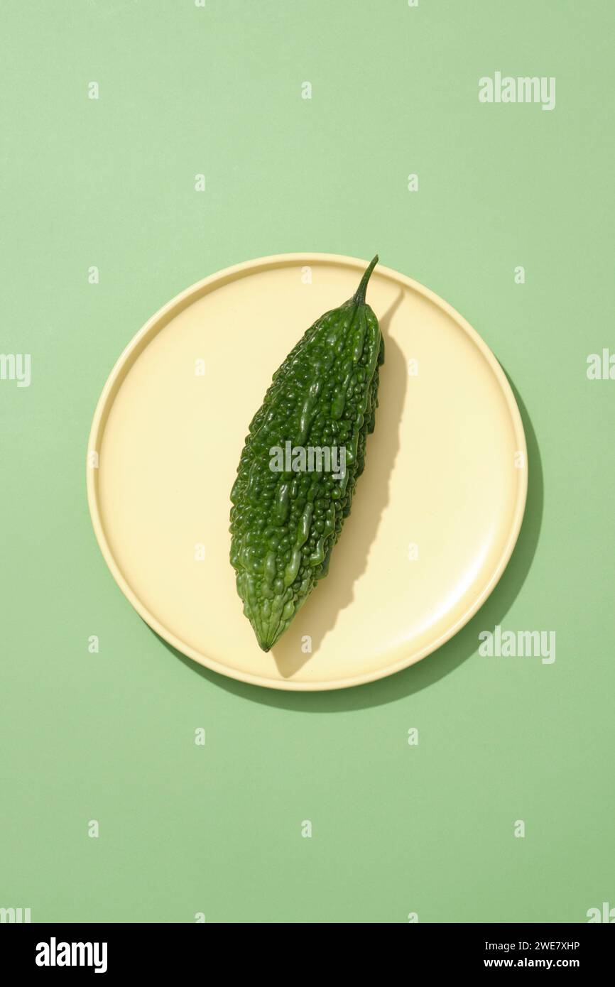 Organic fresh green bitter melon put on a yellow round dish. Bitter ...