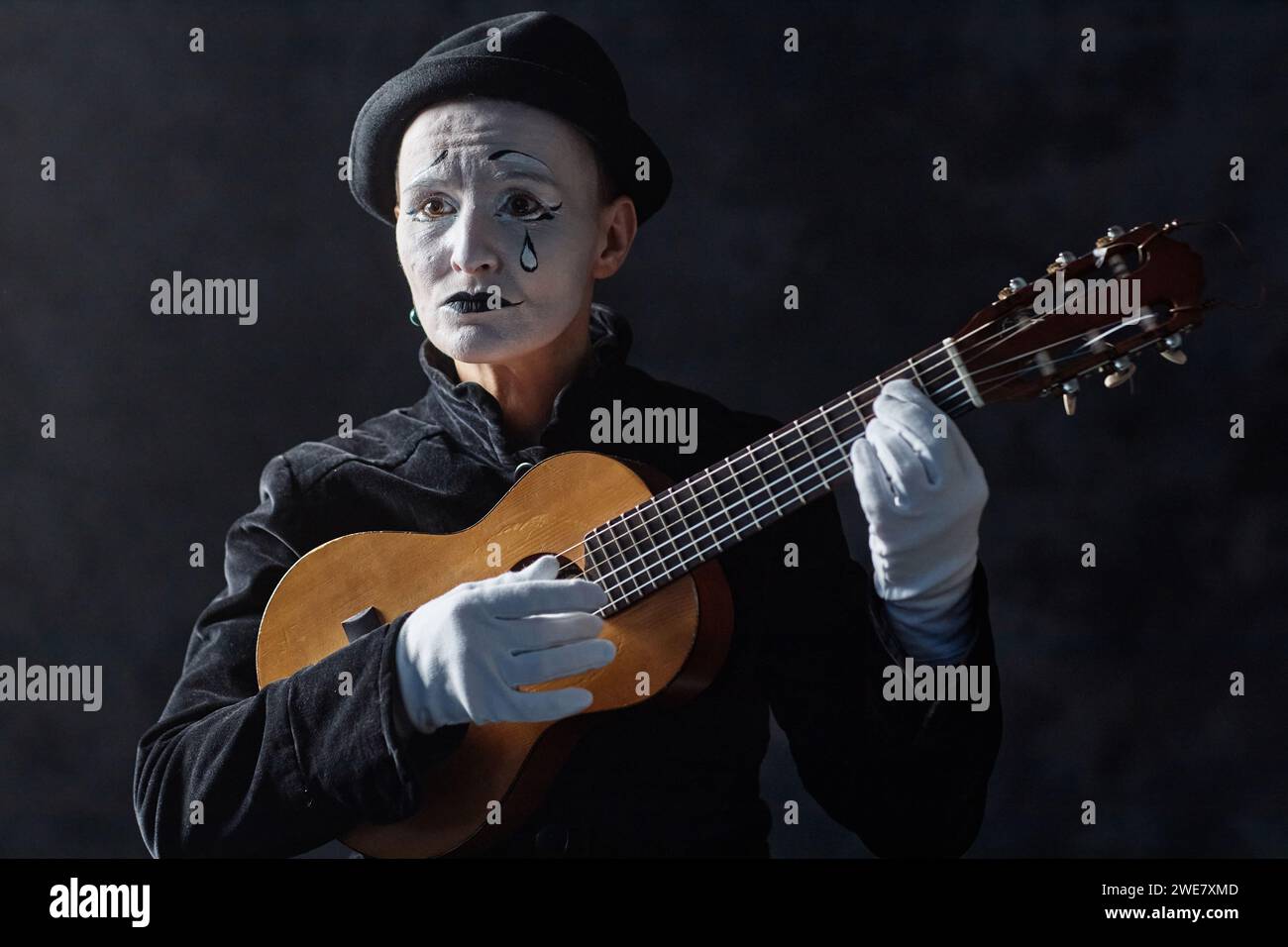 Dramatic waist up portrait of mime artist playing guitar performing on ...