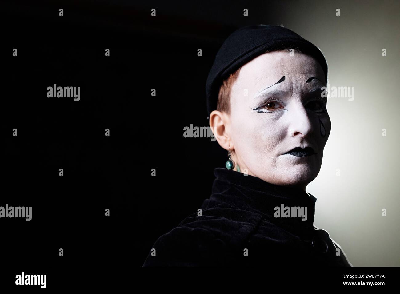 Minimal portrait of sad mime standing in contour lighting and looking ...