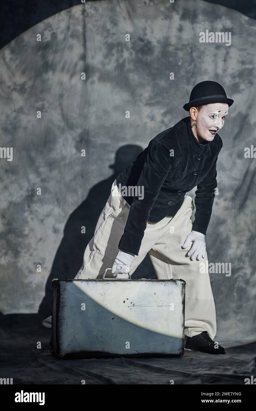 Vertical full length portrait of mime artist performing act with ...