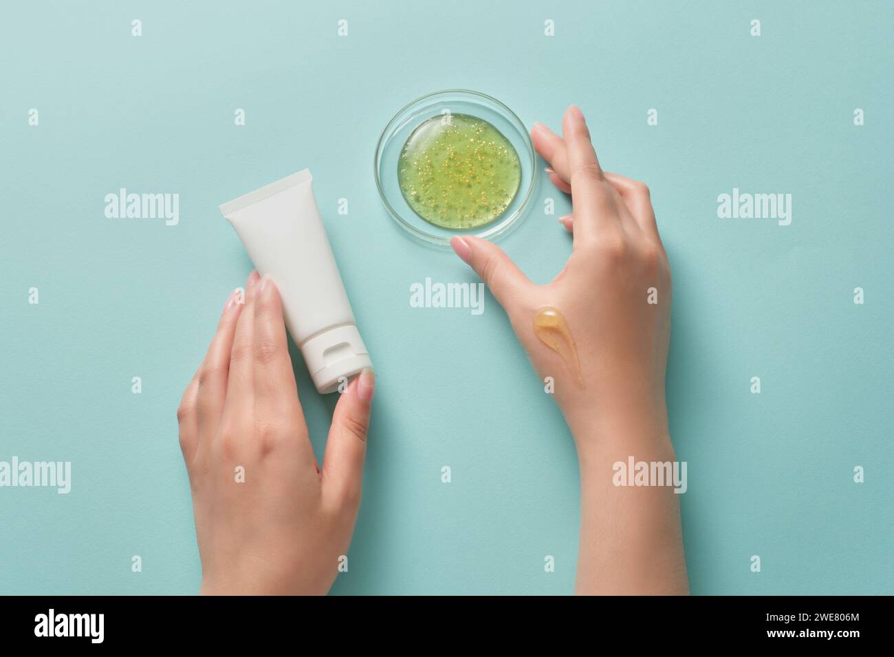 A glass petri dish filled with yellow essence and an unbranded tube are ...