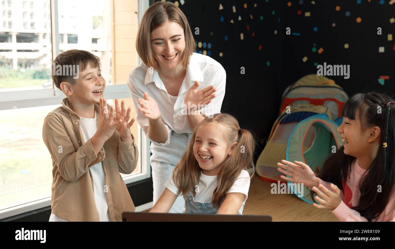 Caucasian teacher and happy students clapping hands to celebrate ...