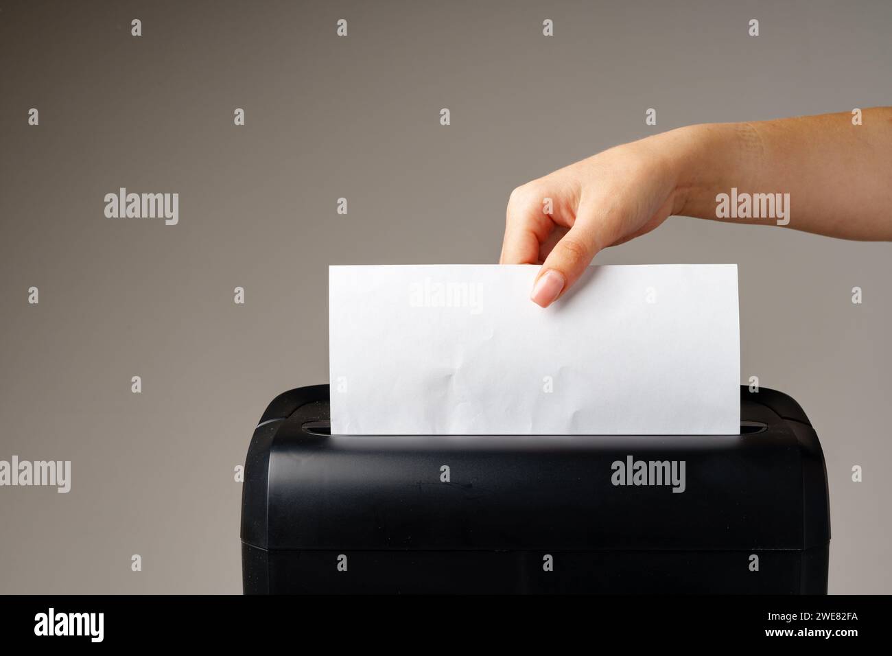 Hand using paper shredding machine against gray background Stock Photo ...