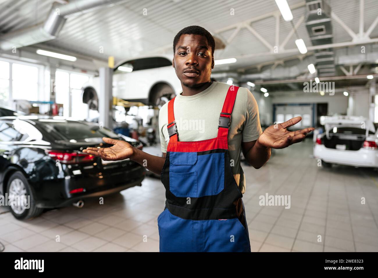 African man mechanic in uniform at the car repair station, portrait ...