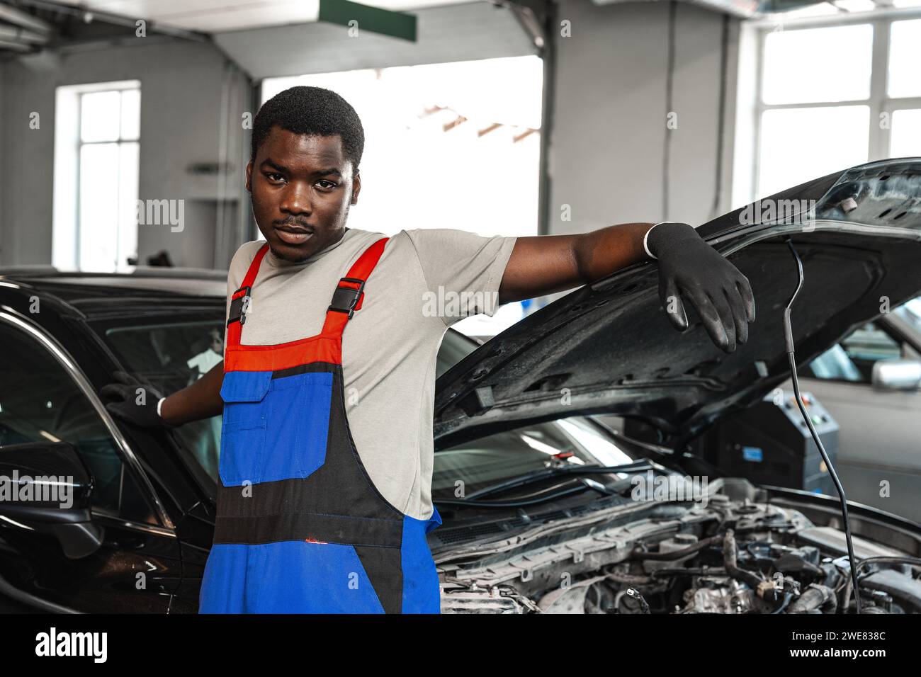 African man mechanic in uniform at the car repair station, portrait ...