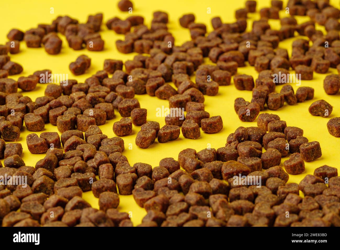 Dry cat food scattered on yellow background studio shot Stock Photo - Alamy