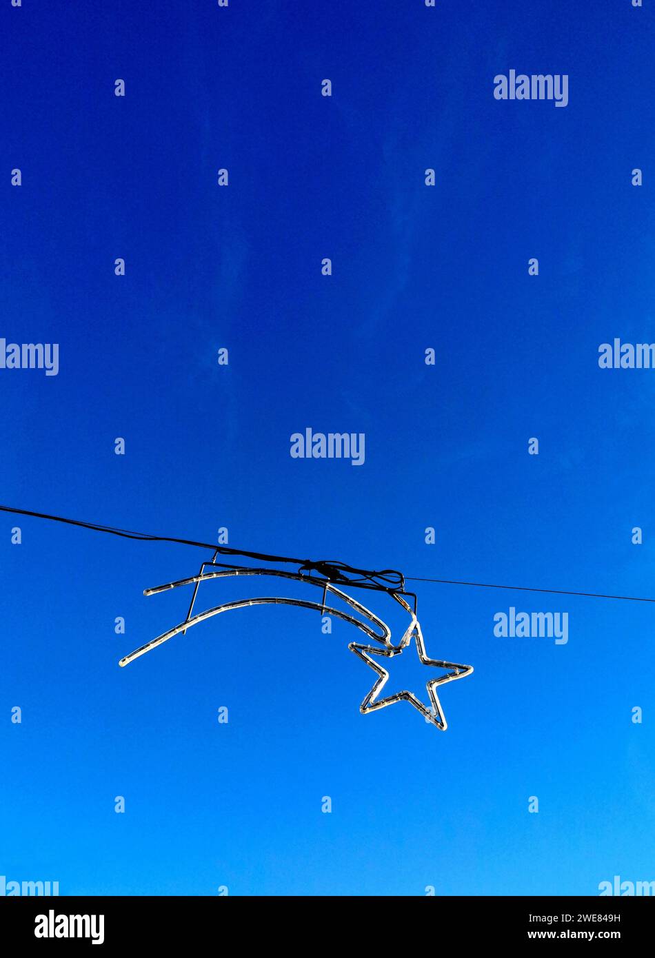 A star-shaped object hanging from an electrical wire against a vibrant ...