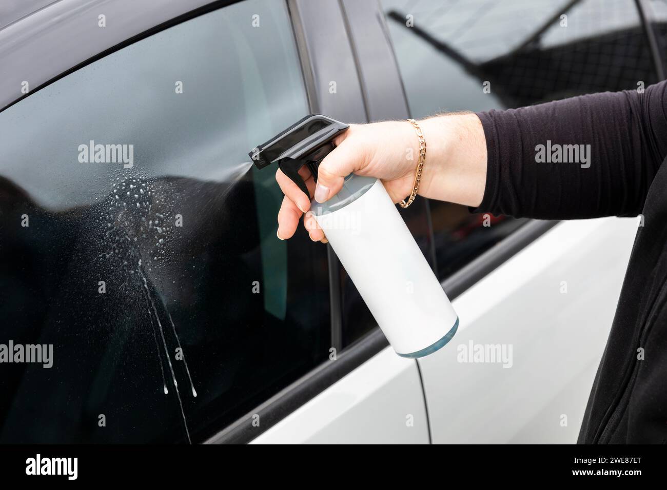 Man spraying a cleaning solution on the car windows, ensuring a clear ...