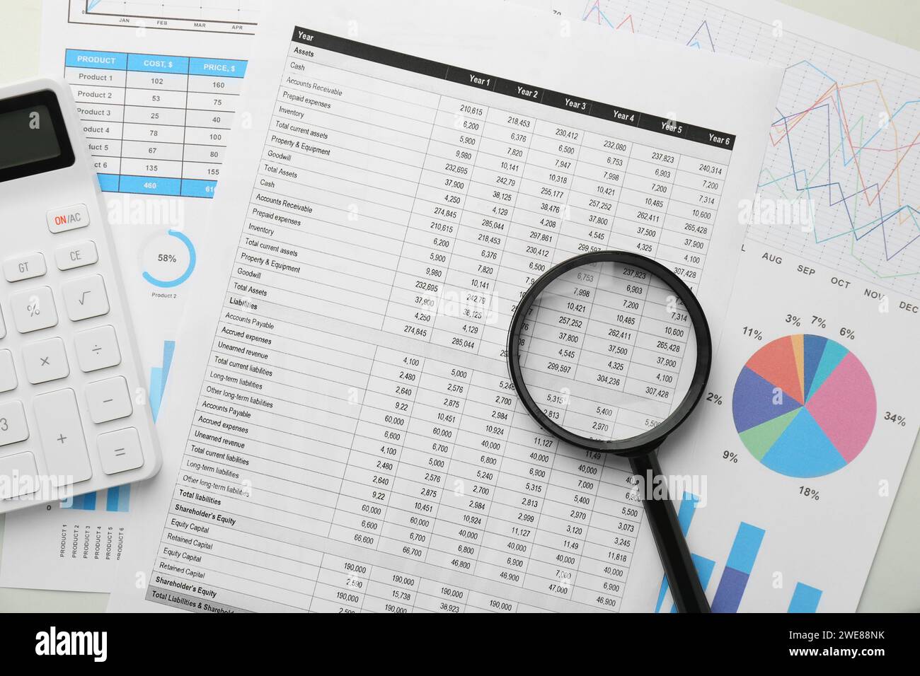 Accounting documents, magnifying glass and calculator on table, top ...