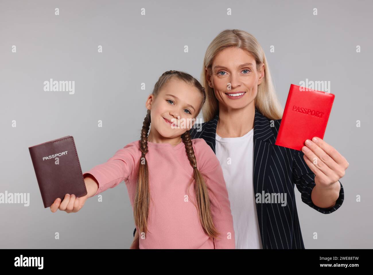 Immigration. Happy woman and her daughter with passports on gray ...
