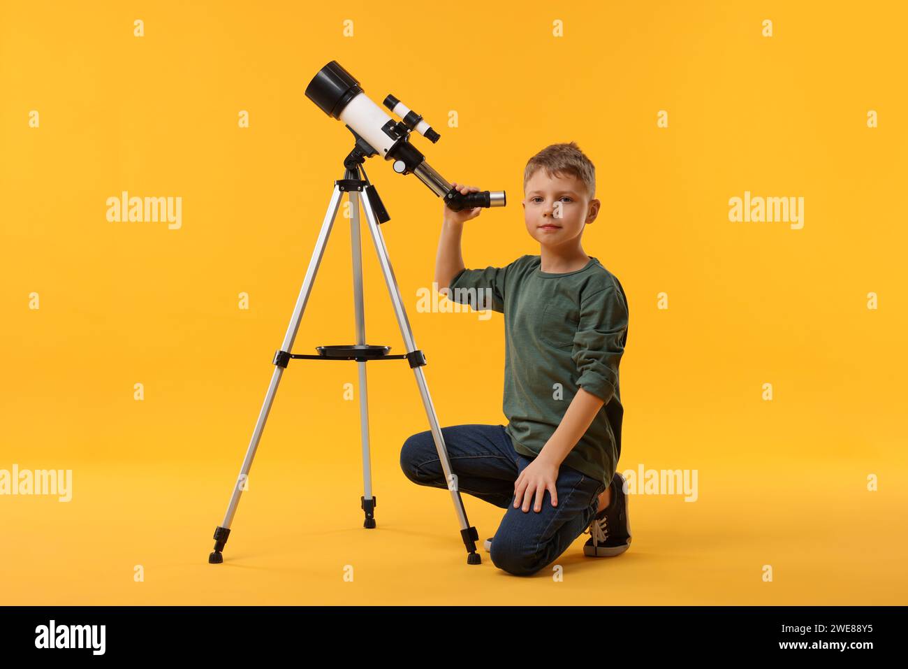 Cute little boy with telescope on orange background Stock Photo - Alamy